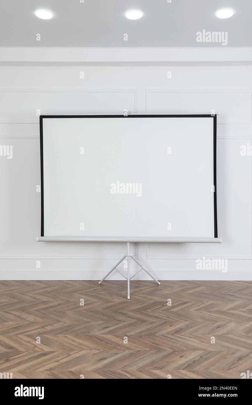 Blank projection screen near white wall indoors. Space for design Stock ...