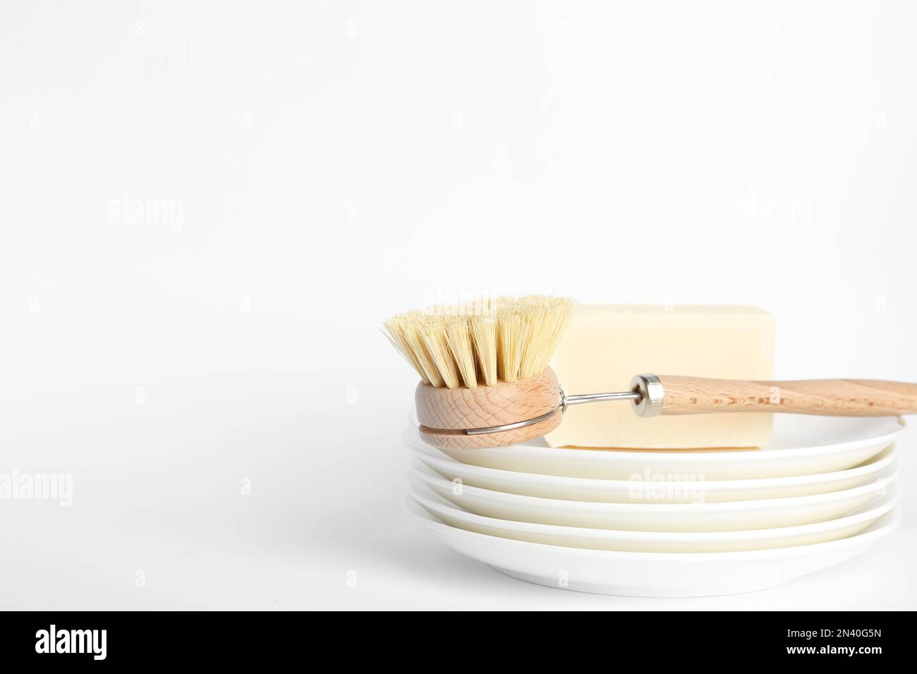 Cleaning brush and soap bar for dish washing on plates against white ...