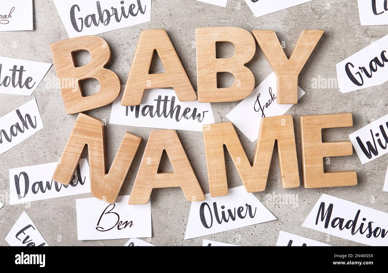 Paper sheets with different baby names and wooden letters on grey ...