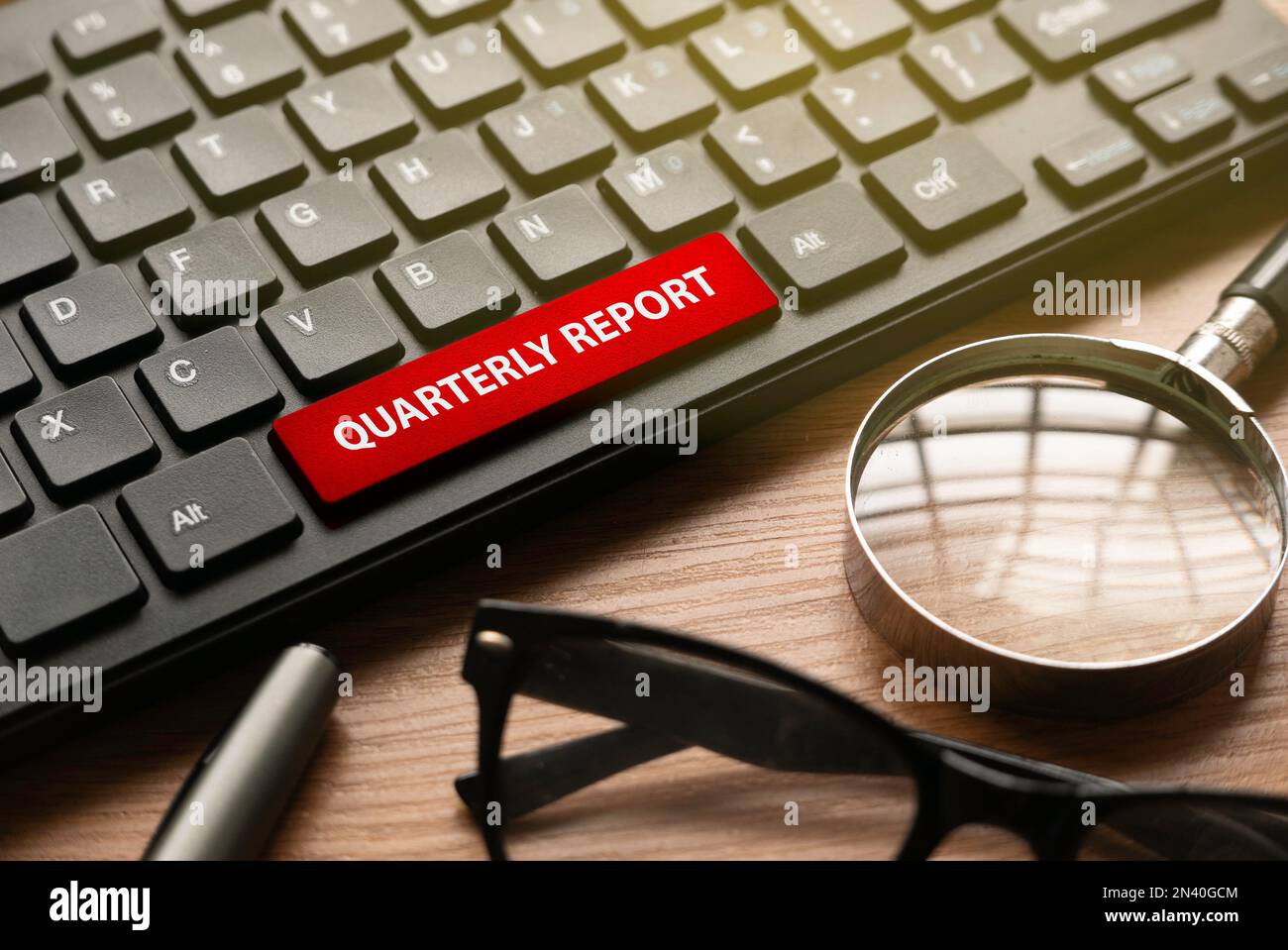 Pen,glasses, magnifying glass and computer key written with QUARTERLY ...