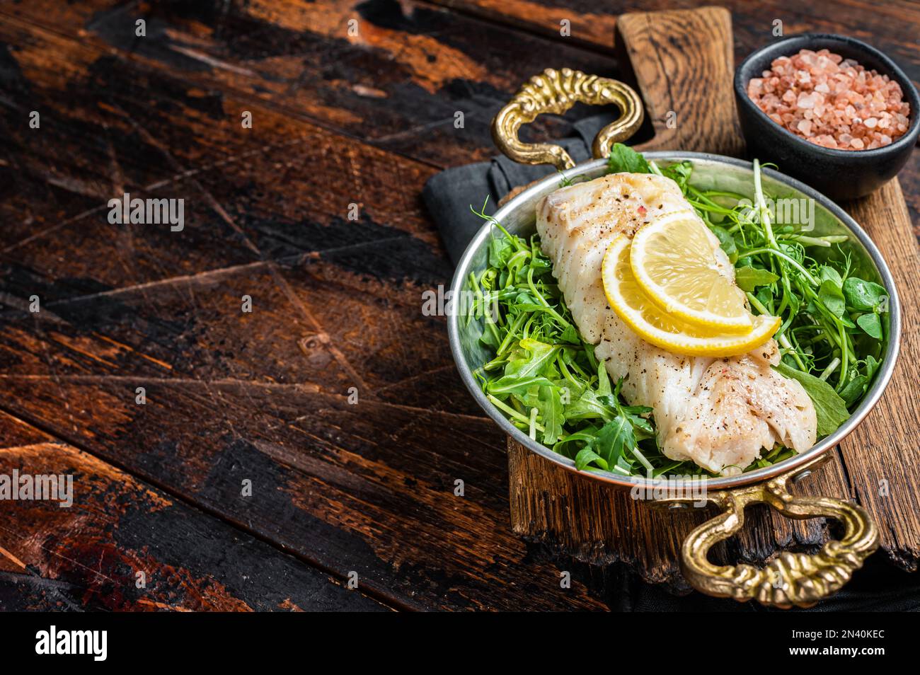 Roasted pollock or coalfish fish fillet served with green salad in a ...