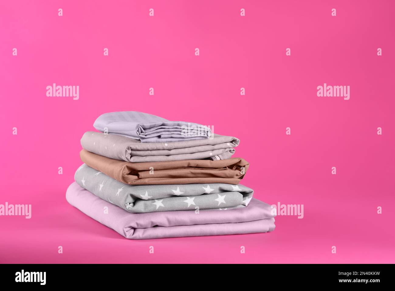 Stack of clean bed sheets on pink background Stock Photo - Alamy