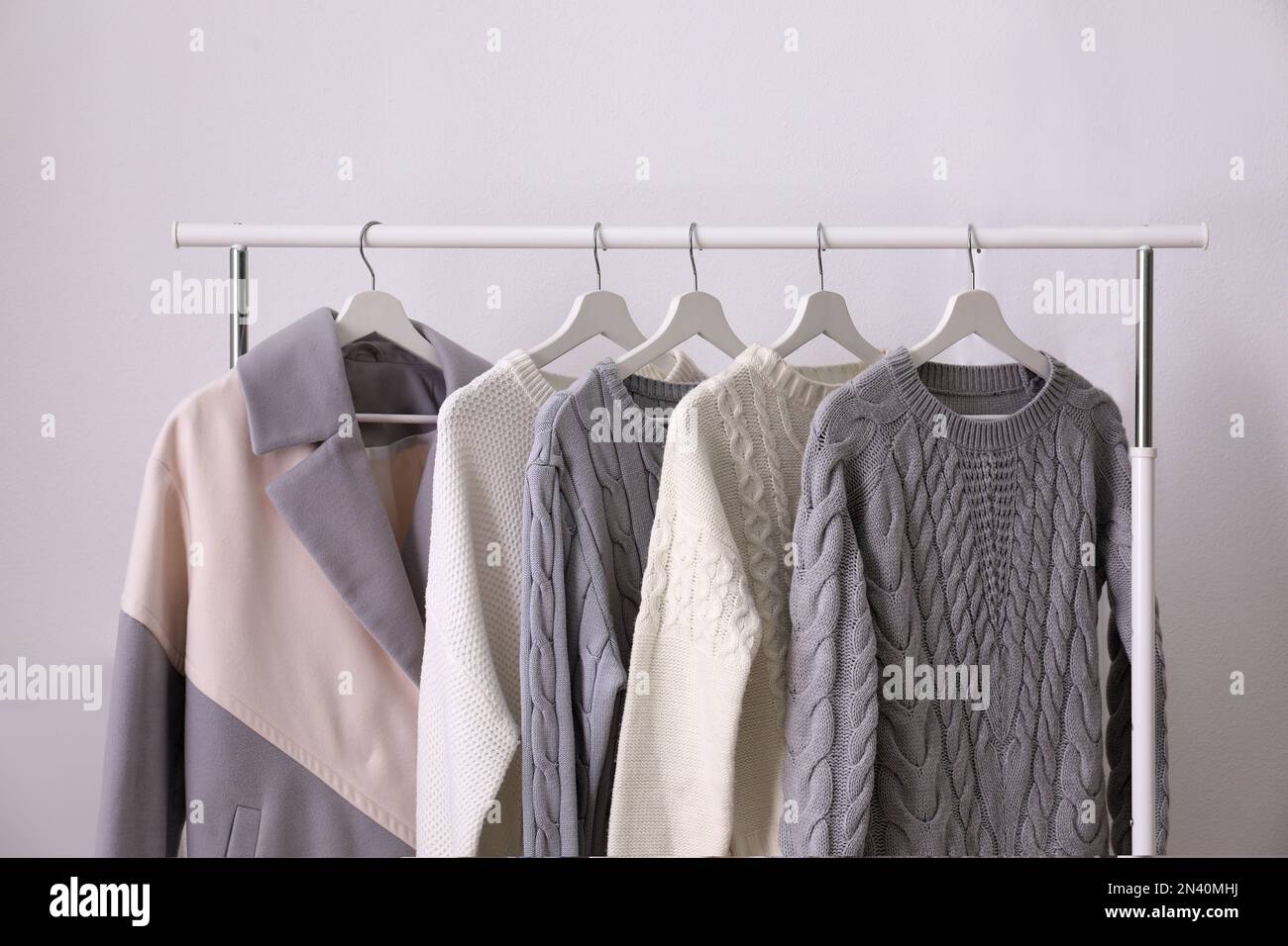 Rack with stylish warm clothes in room Stock Photo - Alamy