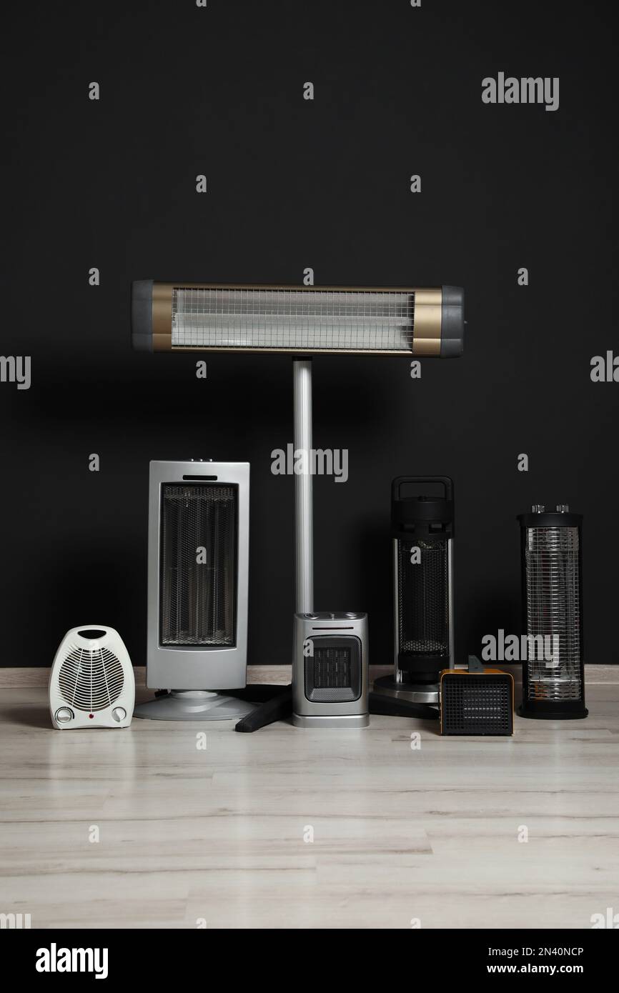 Set of different modern electric heaters near black wall Stock Photo ...