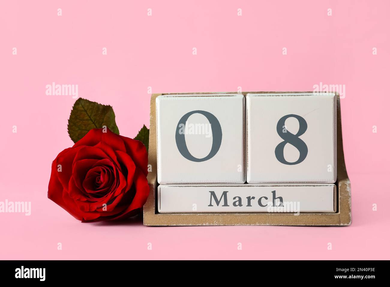 Wooden block calendar with date 8th of March and rose on pink ...