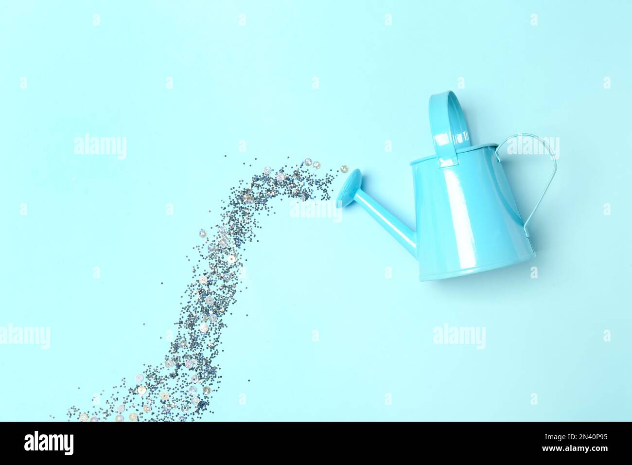 Watering can with silver glitter confetti imitating water flow on cyan ...