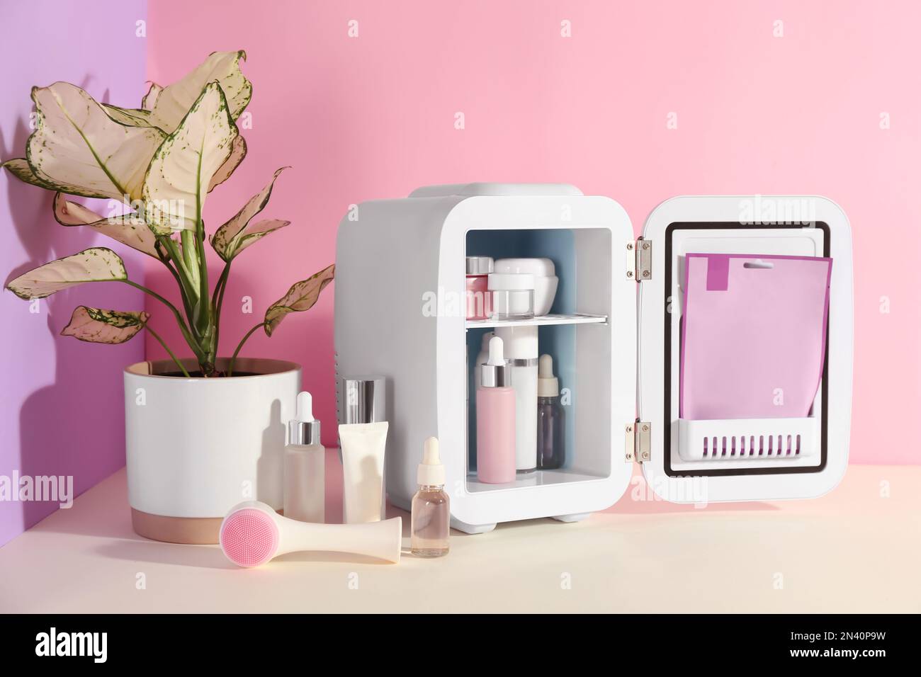 Open cosmetic refrigerator and skin care products on color background ...