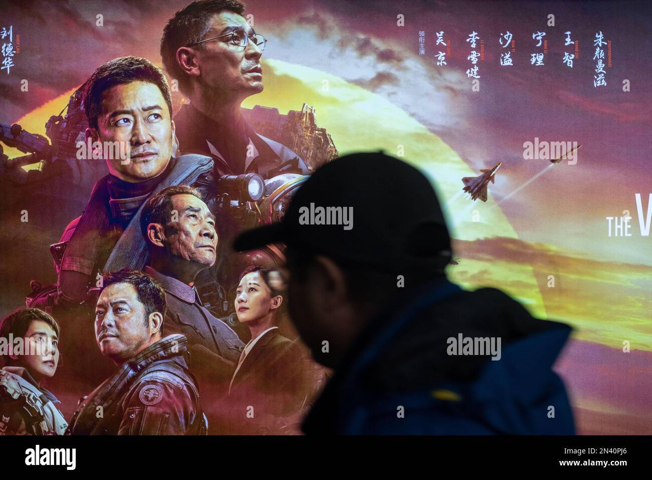 Man past a poster of Chinese film "The Wandering Earth II" at a cinema ...