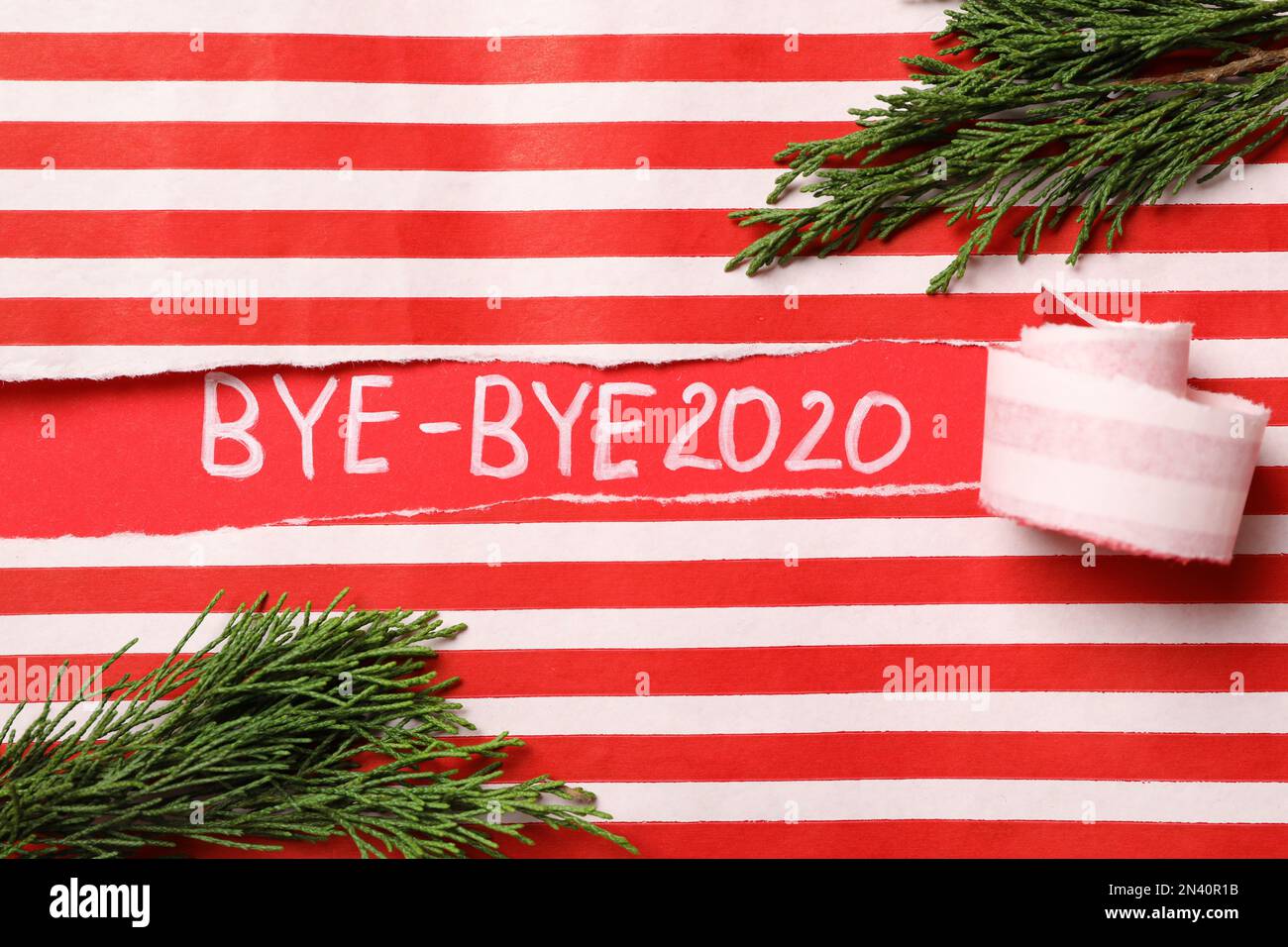 Thuja branches and text Bye-bye 2020 on red background, view through ...