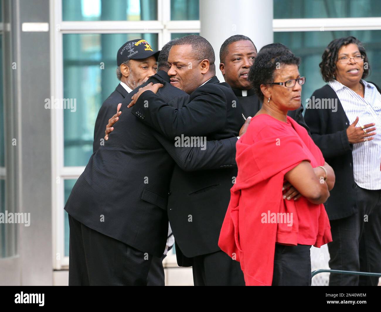 Rev. Timothy Tyler, third from left, hugs Calvin Booker, the brother of ...