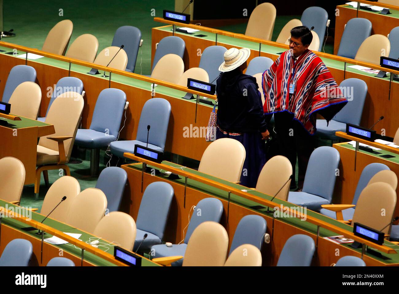 Delegates in traditional attire stand in the General Assembly hall at ...