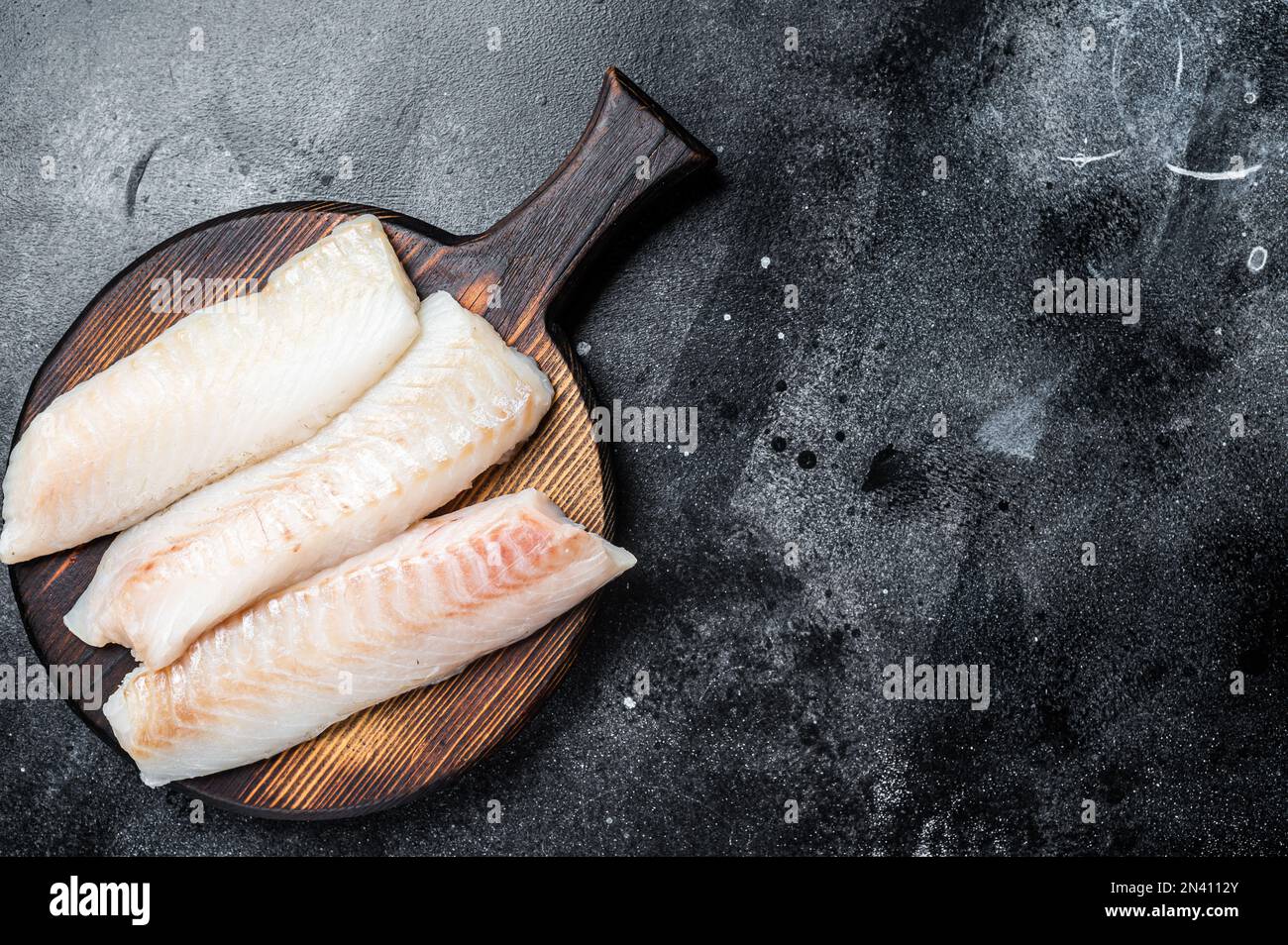 Fillets of codfish, raw cod fish meat. Black background. Top view. Copy ...