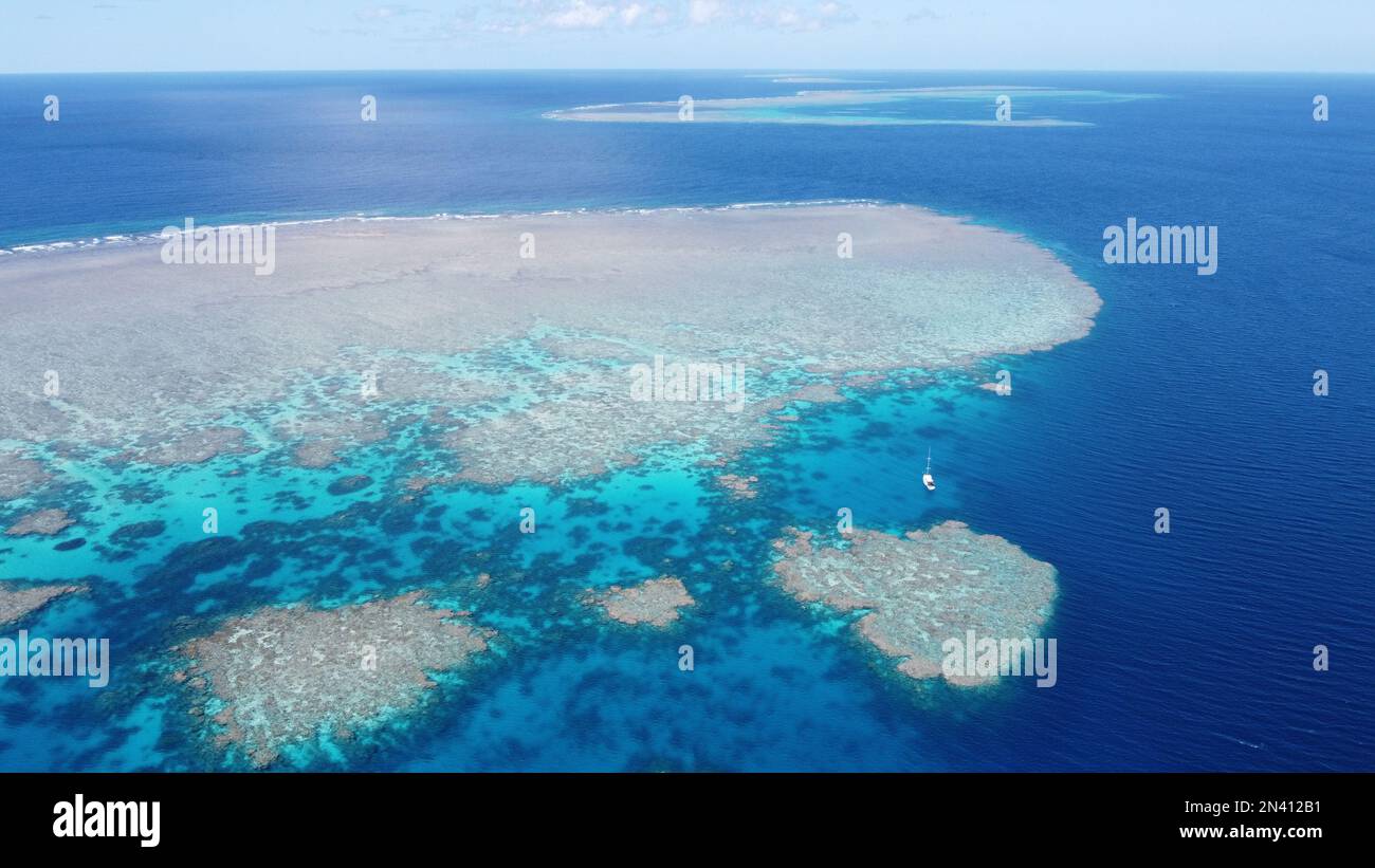 Aerial shot of a sailing boat anchored in a lagoon surroneded by reef ...