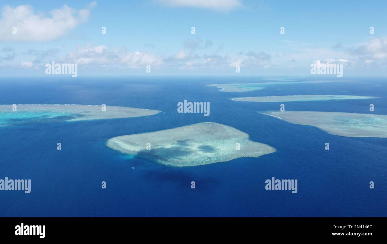 Aerial shot of several reefs with deep blue water between them and a ...