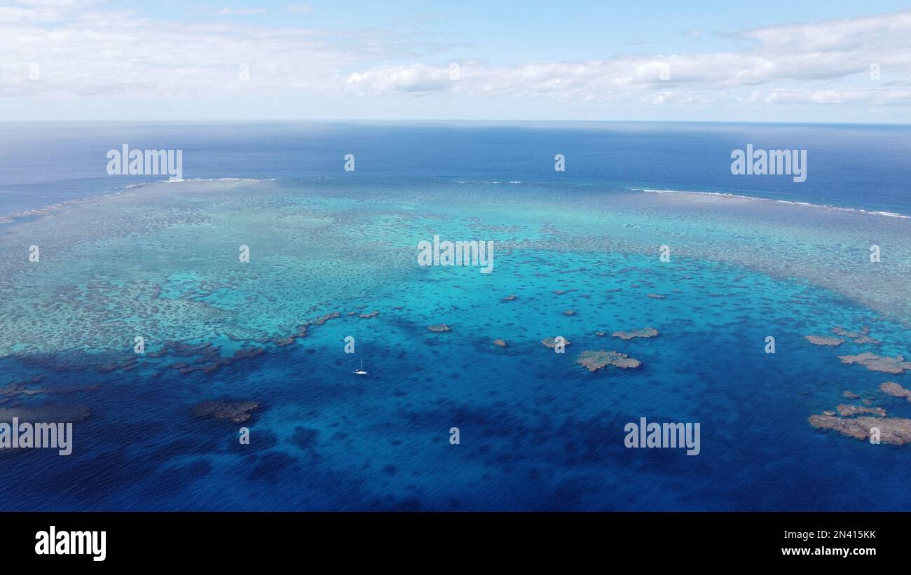 Sailing boat anchored in a lagoon surrounded by coral reef taken on the ...