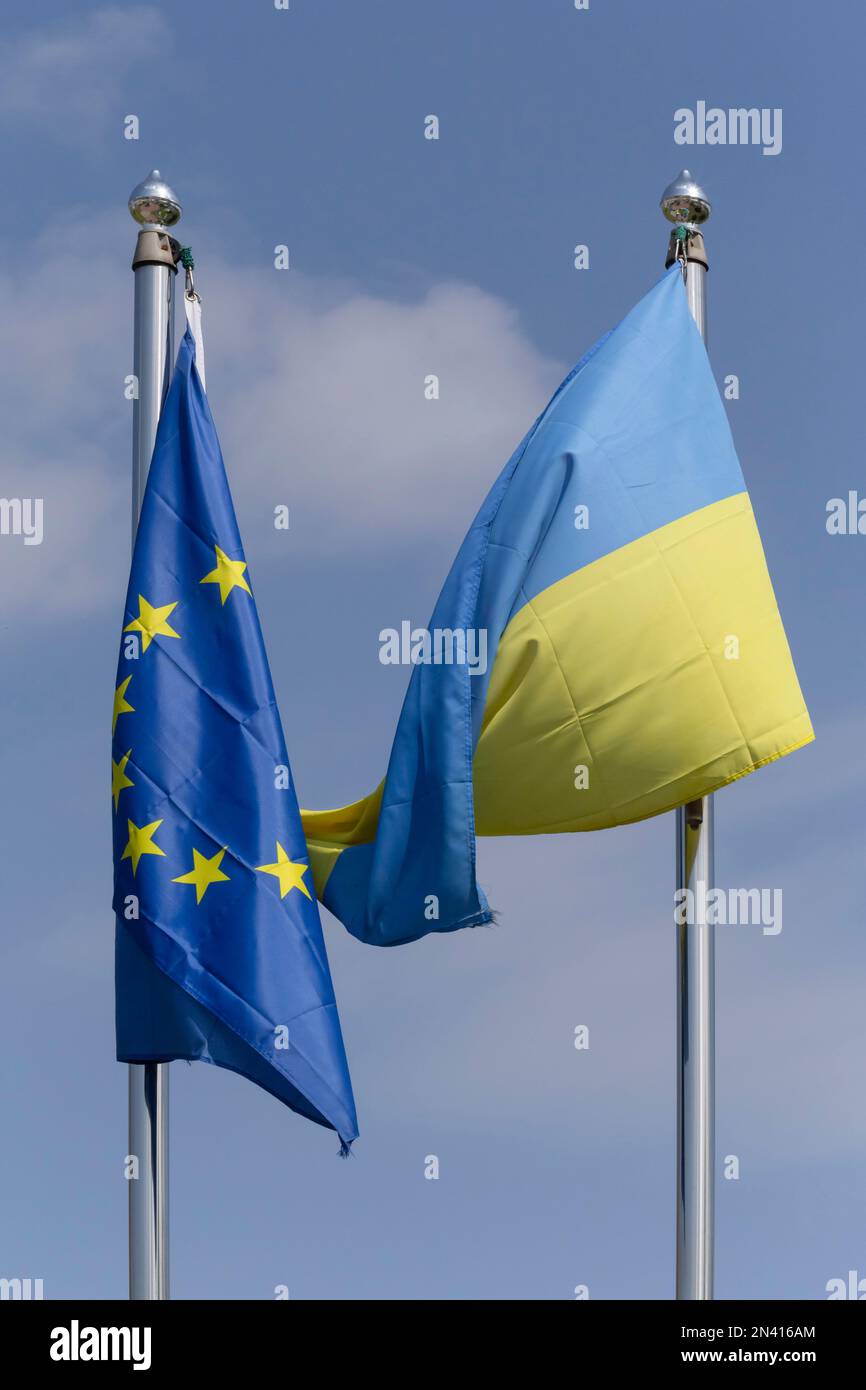 European Union and Ukrainian flags hanging on flagpoles against blue ...