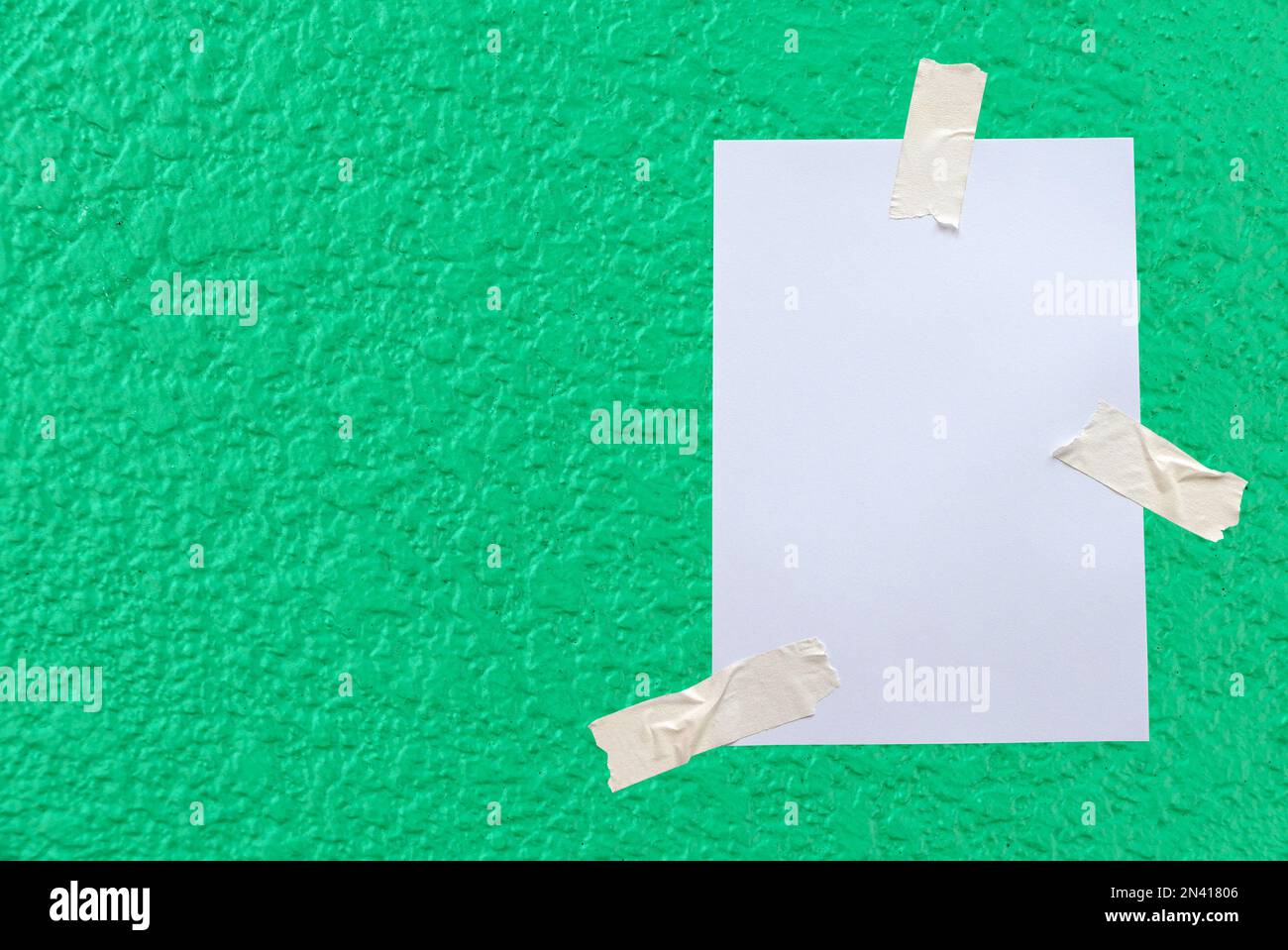 Blank white paper attached to the green wall with tape Stock Photo - Alamy
