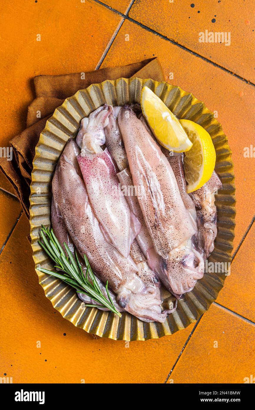 Whole Raw squid with herbs and lemon, fresh Seafood. Orange background ...