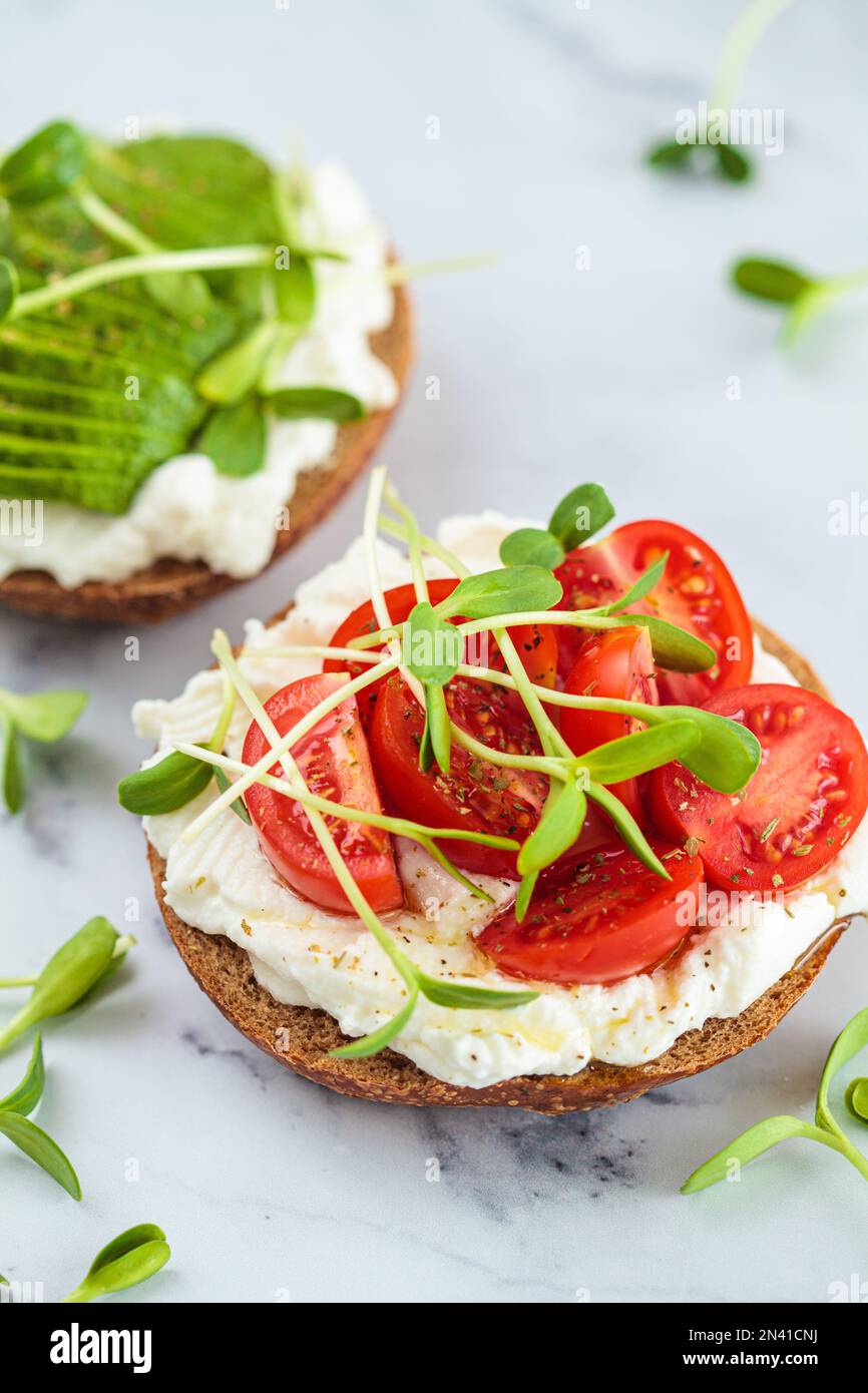 Bun toast with cream cheese, cherry tomatoes and micro greens. Healthy ...