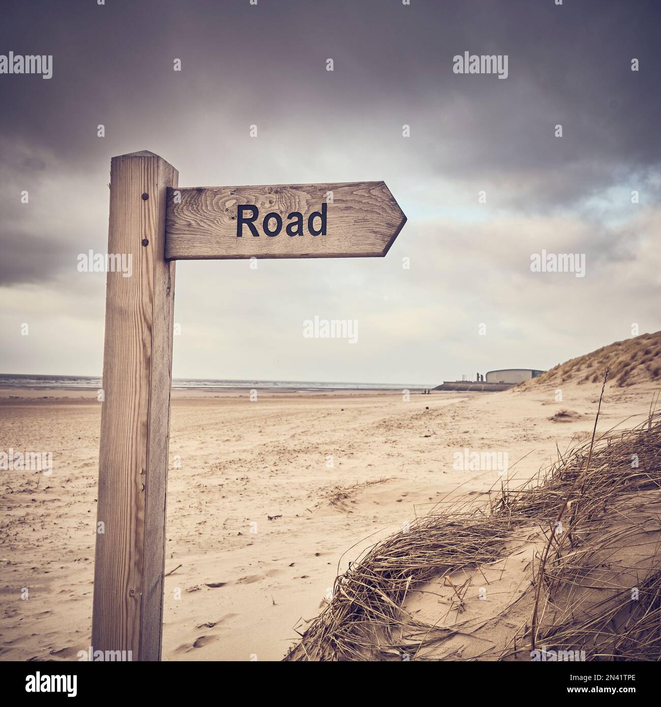 Wooden sign on beach pointing in direction of road Stock Photo - Alamy