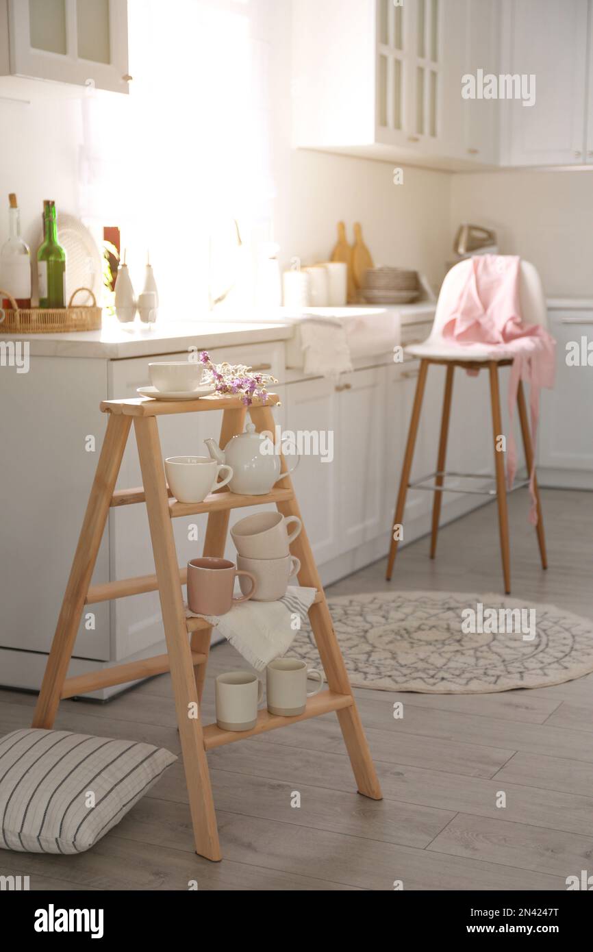 Decorative ladder with different dishware and field flowers bouquet in ...