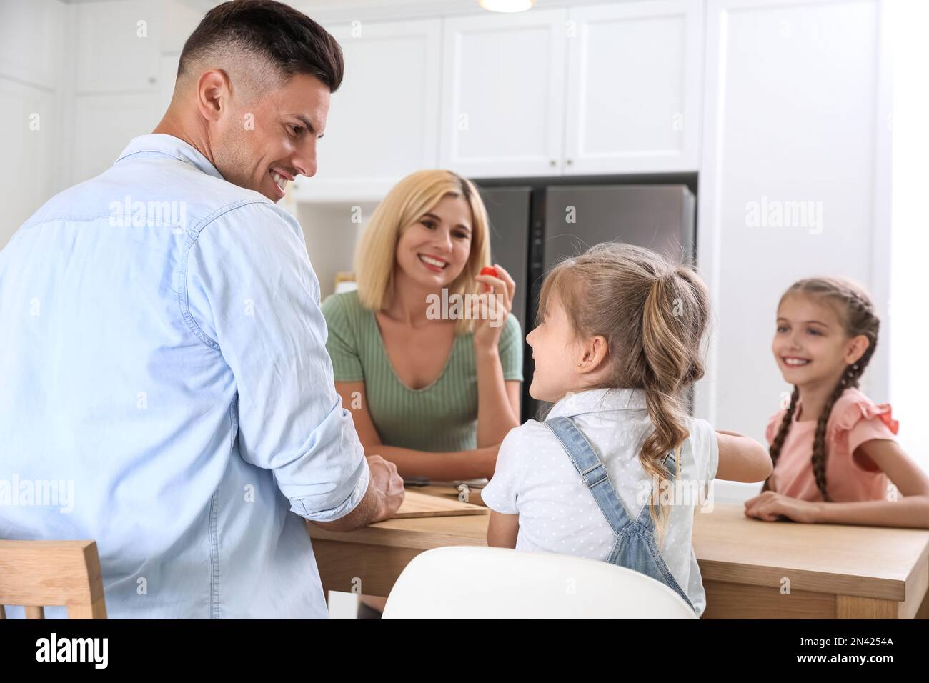 Happy family cooking together at table in modern kitchen Stock Photo ...