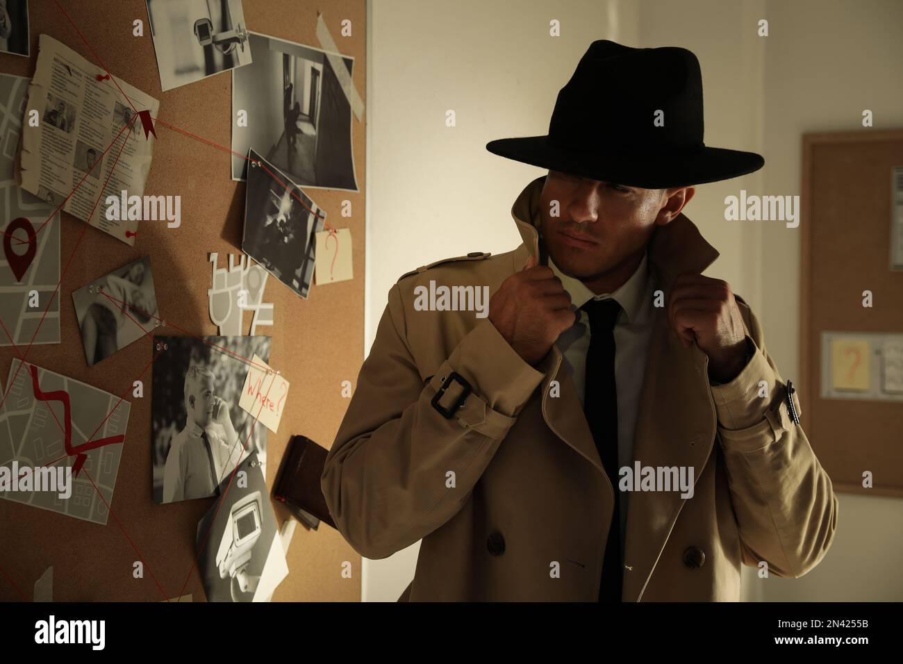 Detective near evidence board in his office Stock Photo - Alamy