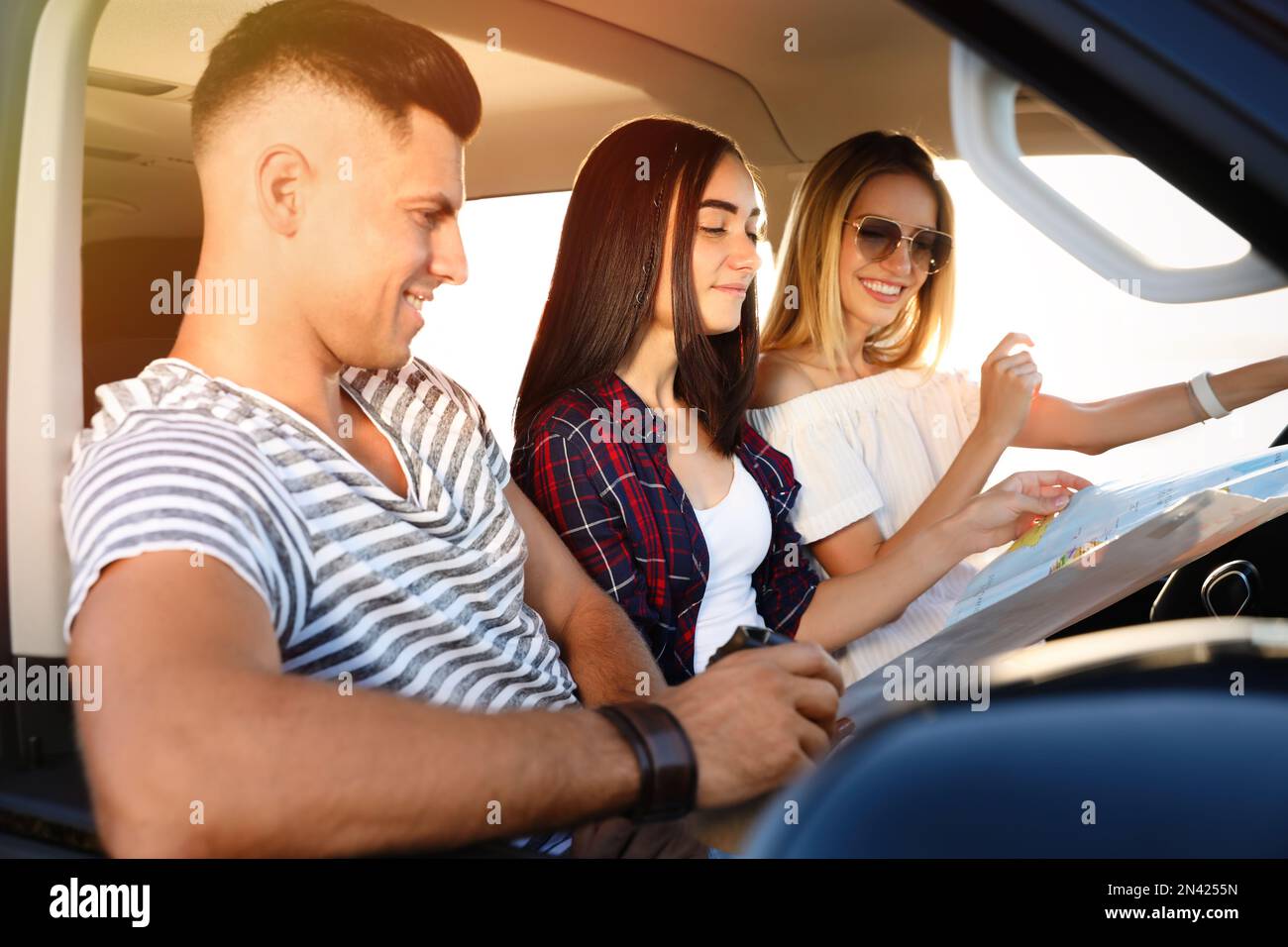 Happy friends with map in car on road trip Stock Photo - Alamy