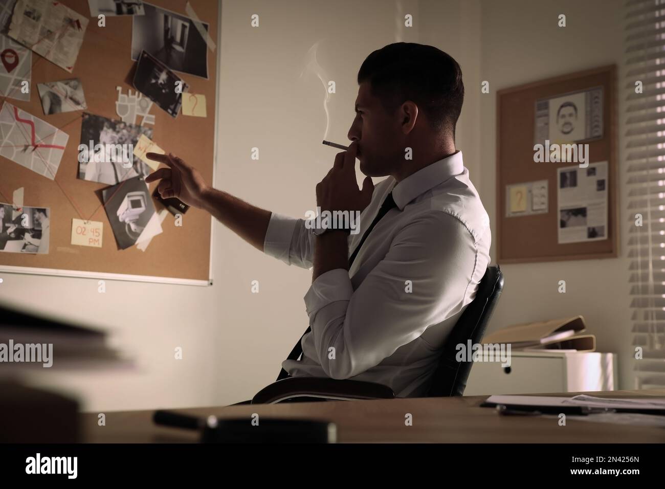 Detective looking at evidence board in office Stock Photo - Alamy