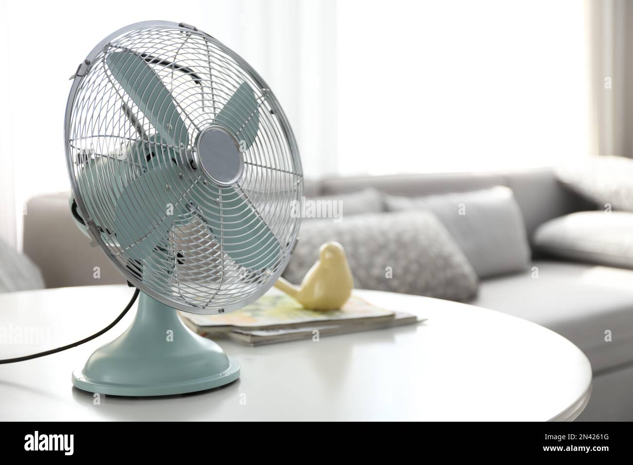 Modern electric fan on table in living room, space for text. Summer ...