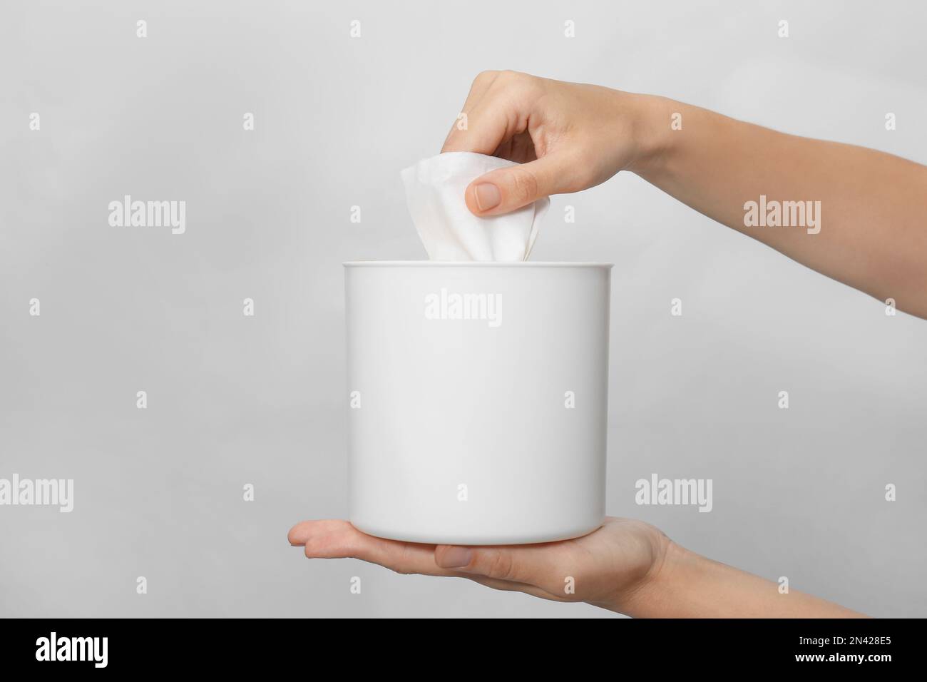 Woman taking paper tissue from holder on light background, closeup ...