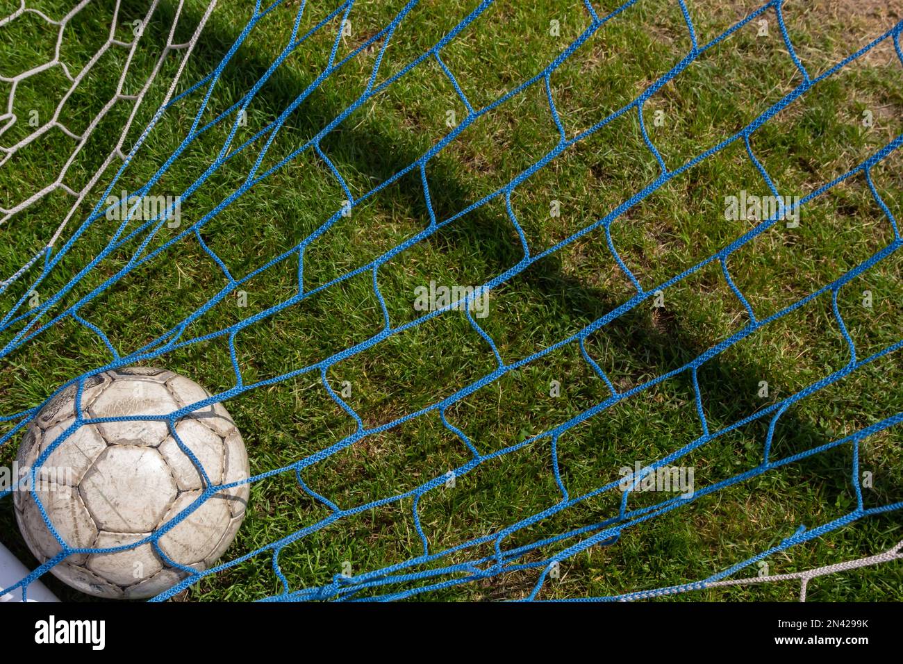 old soccer ball in the net on the background of grass soccer field ...