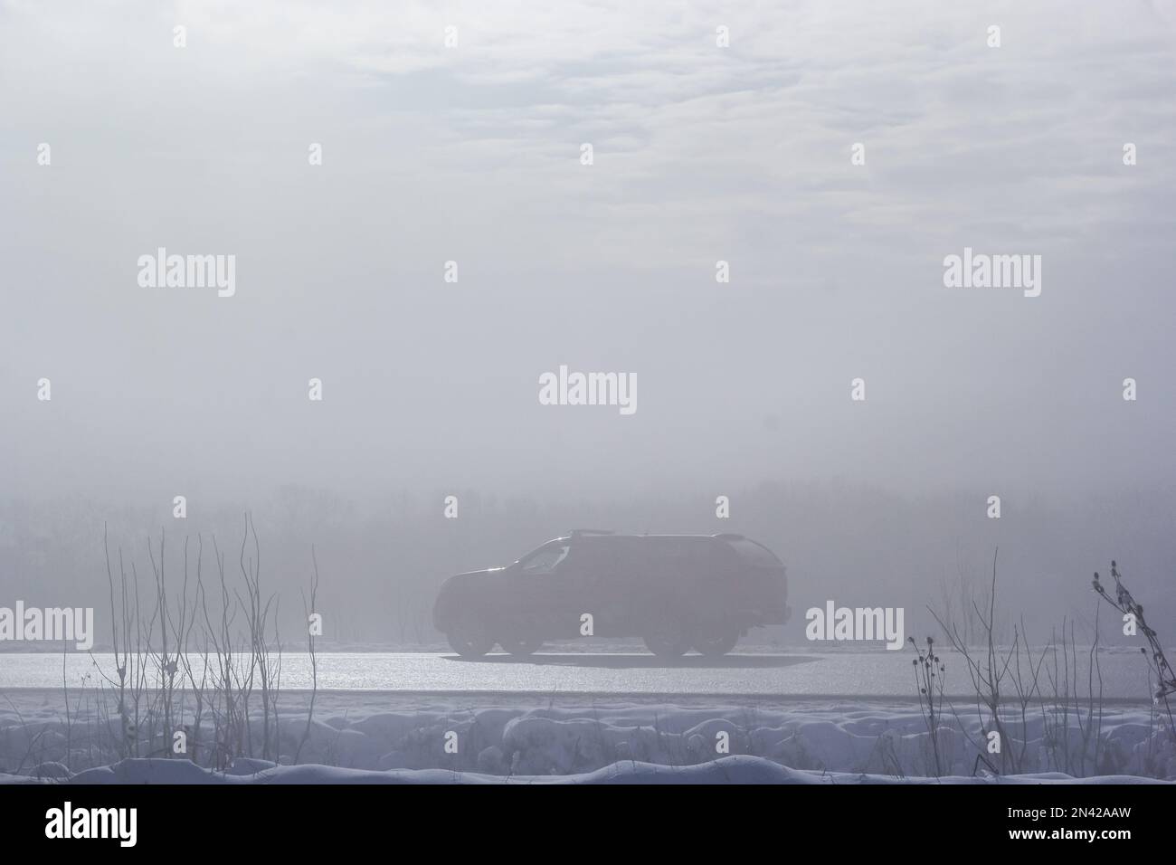 Passenger car in the fog on a winter road with large snowdrifts on the ...