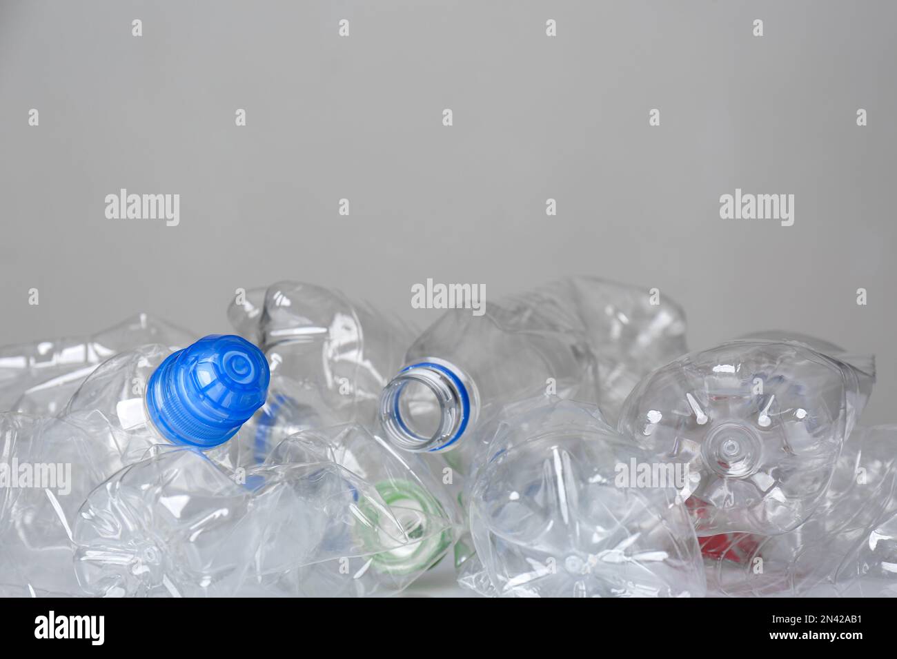 Many used plastic bottles against light background, space for text ...