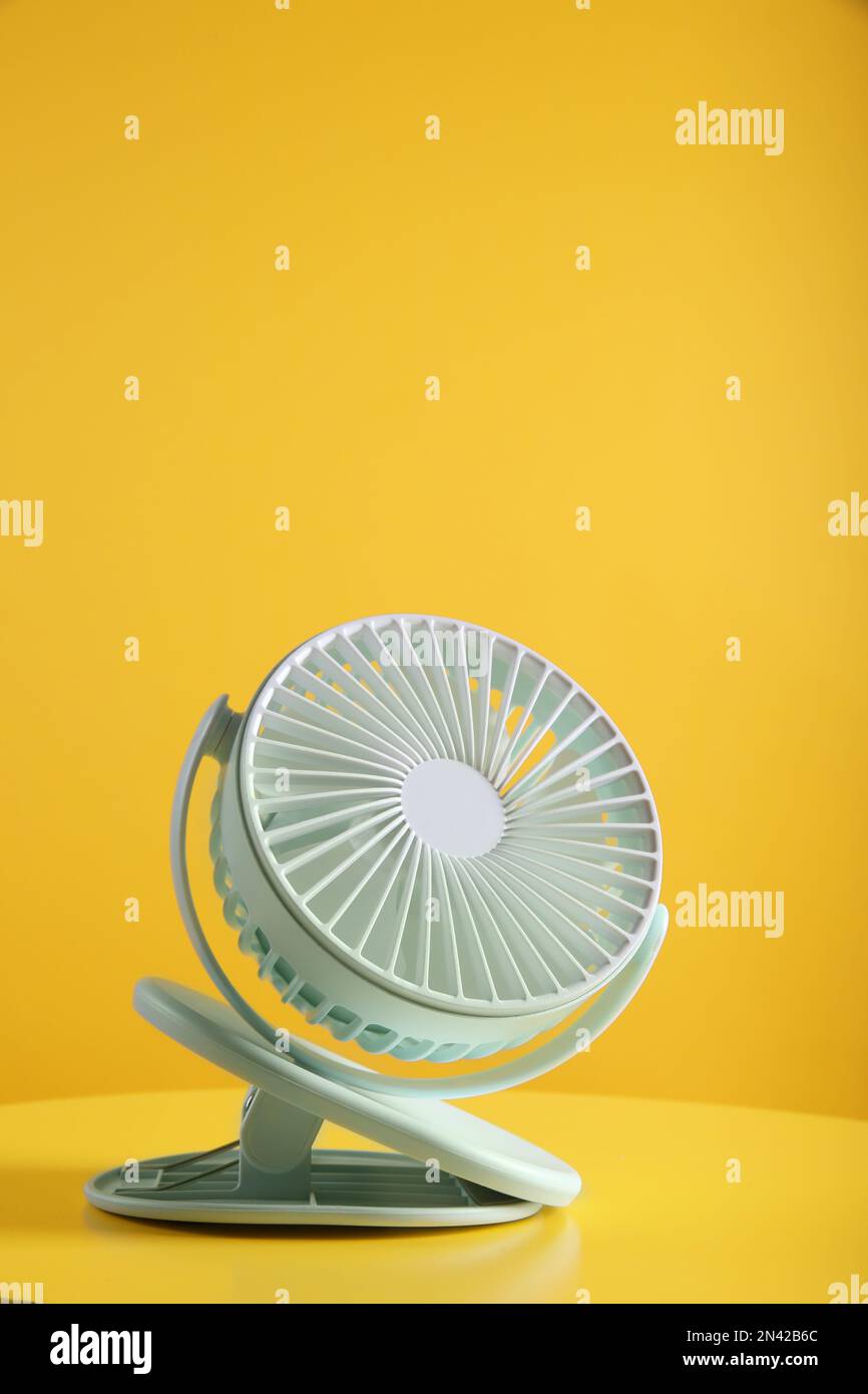 Modern electric fan on table against yellow background Stock Photo - Alamy