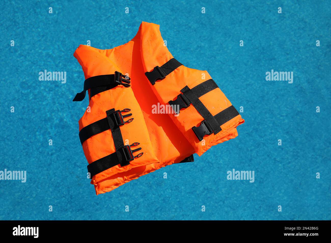 Bright orange life jacket floating in swimming pool, top view Stock ...