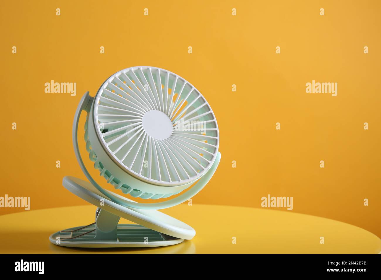 Modern electric fan on yellow table. Space for text Stock Photo - Alamy