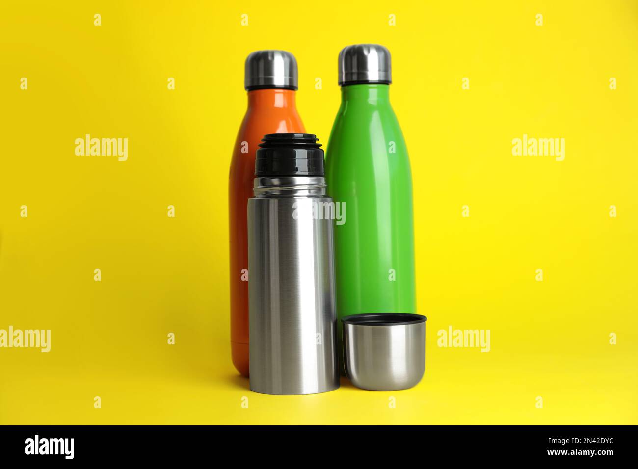 Stylish stainless thermo bottles on yellow background Stock Photo - Alamy