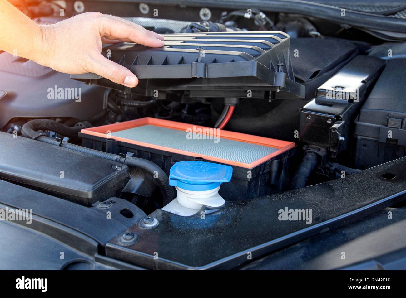 Replacing an old dirty air filter in the engine compartment of a car ...