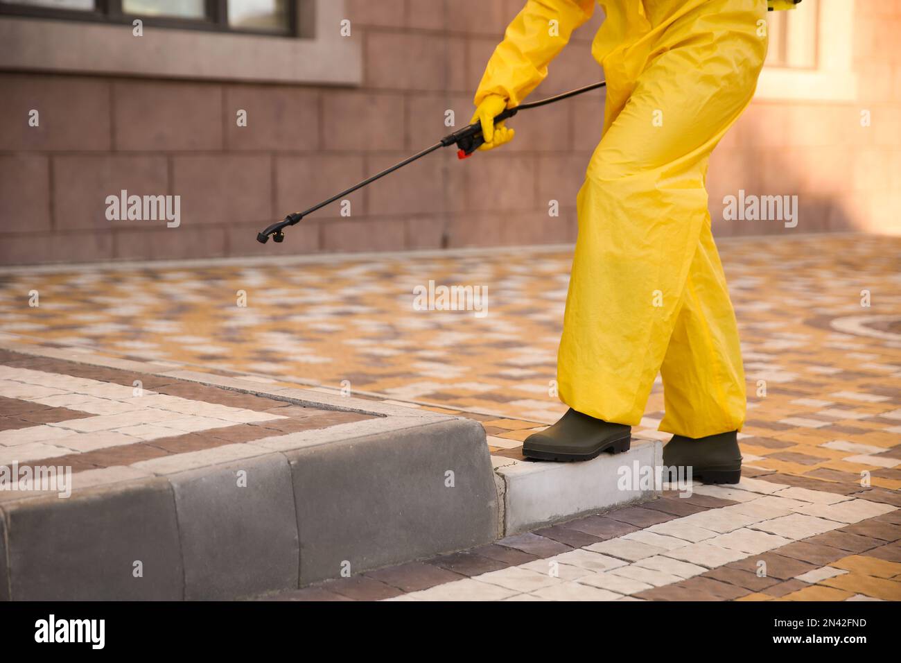 Person in hazmat suit disinfecting street with sprayer, closeup ...