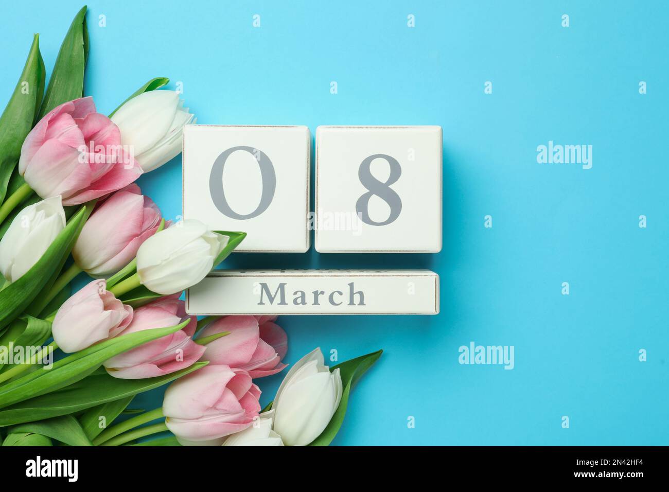 Wooden block calendar with date 8th of March and tulips on light blue ...