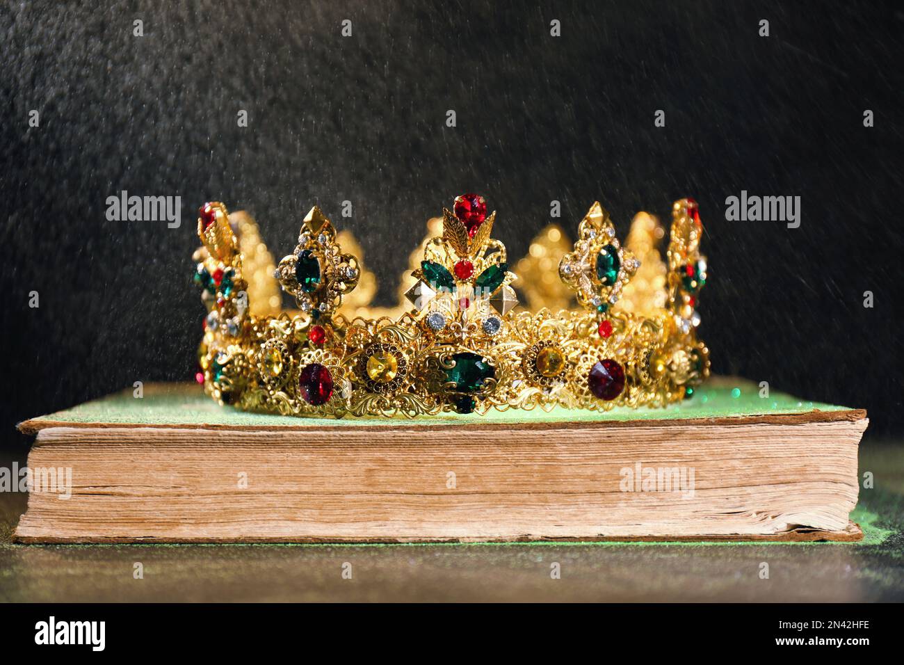 Beautiful golden crown on old book against black background. Fantasy ...