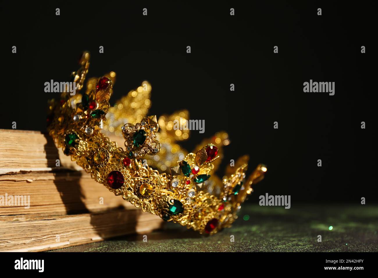 Beautiful golden crown and old books on black background. Fantasy item ...