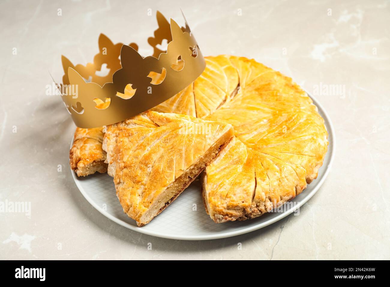 Traditional galette des Rois with paper crown on light grey marble ...