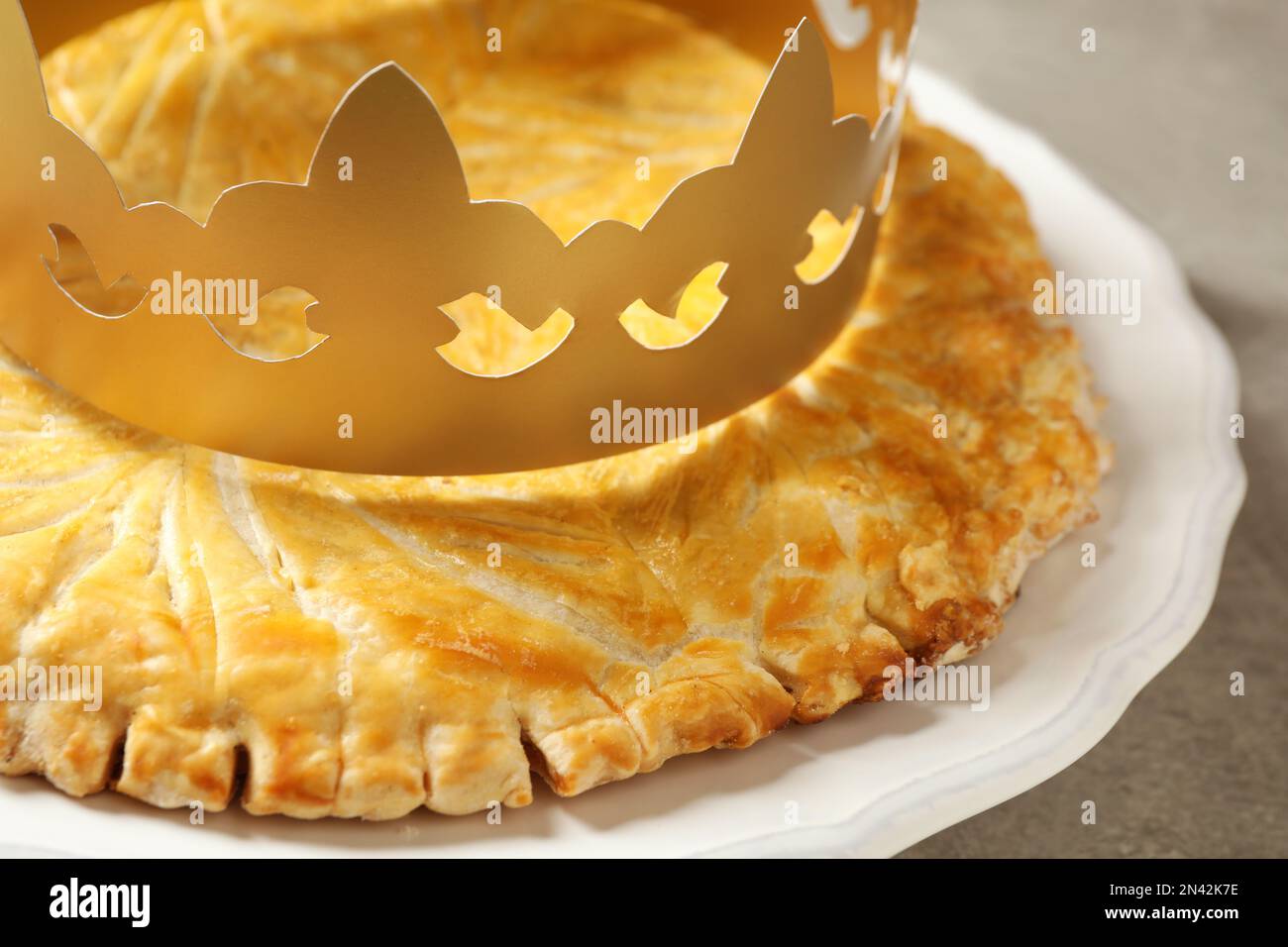 Traditional galette des Rois with paper crown on table, closeup Stock ...