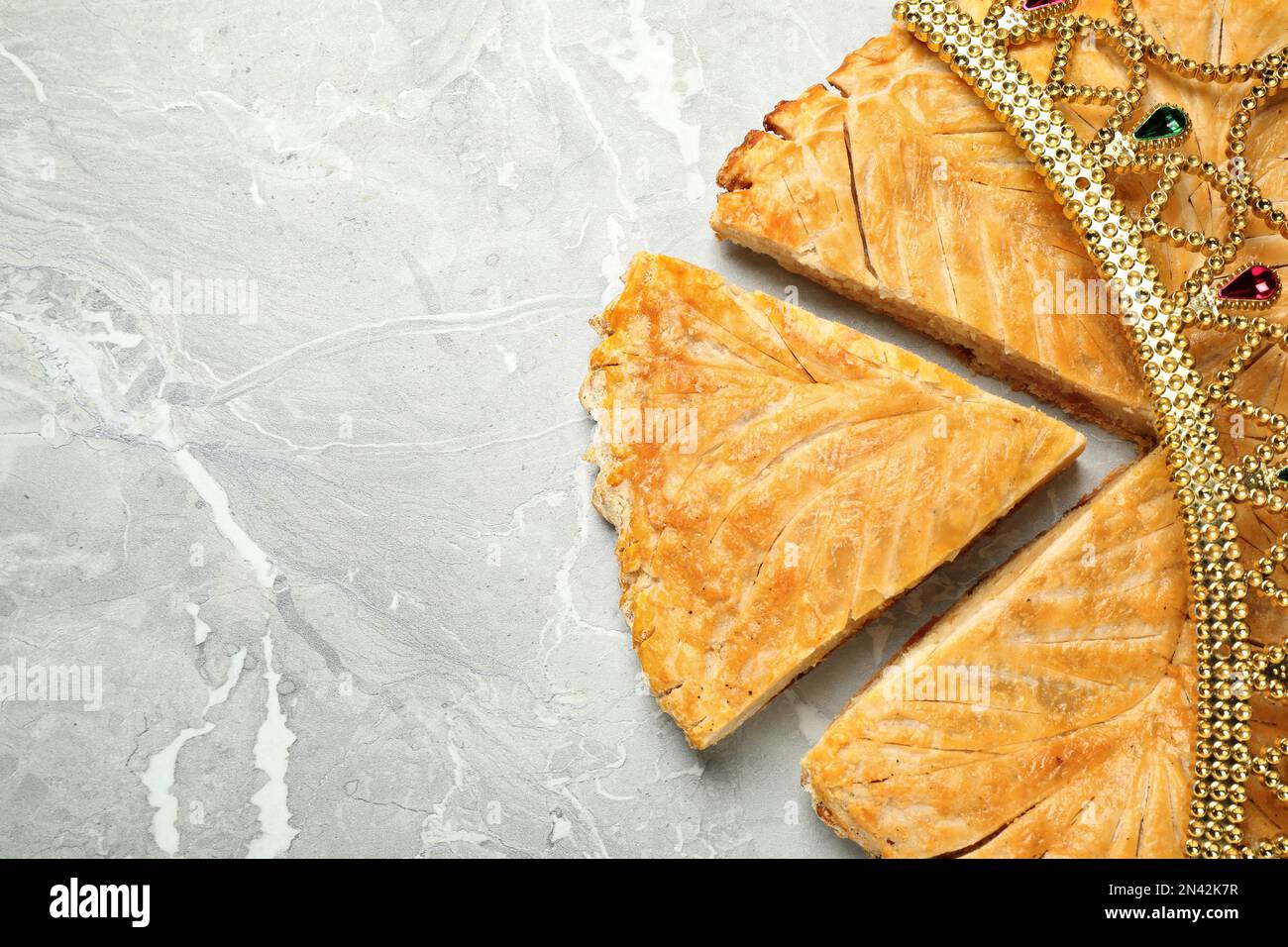 Traditional galette des Rois with decorative crown on grey marble table ...