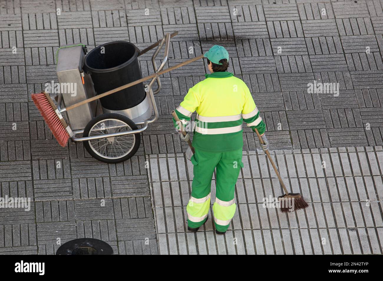 Street sweeper working on a sidewalk with her shovel, cart and broom ...