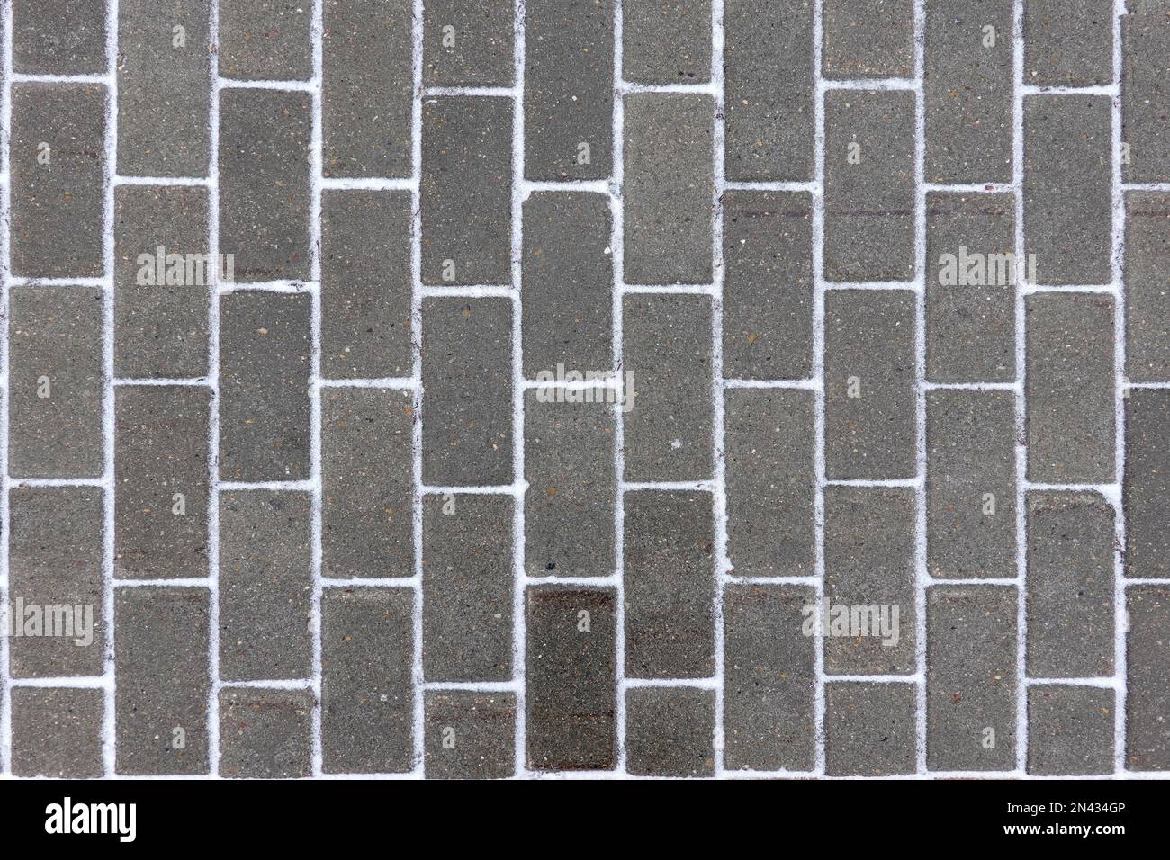 Dark gray paving slabs as background with snow stipes between blocks ...
