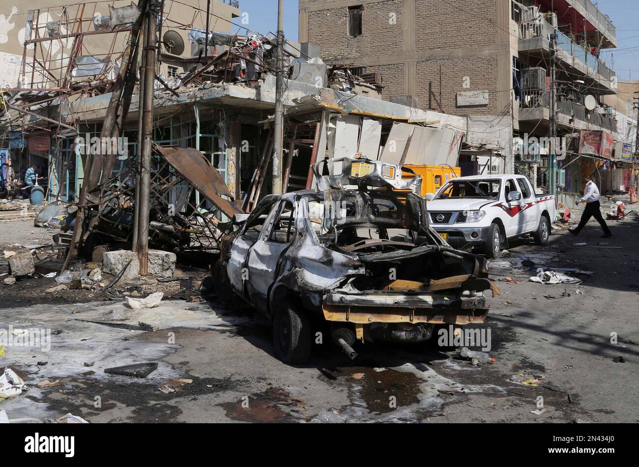 Civilians inspect the scene of a car bomb explosion in Baghdad, Iraq ...