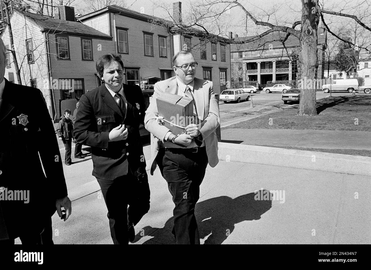 Former Tufts University Professor William Douglas of Sharon, Mass., is escorted in handcuffs by ...